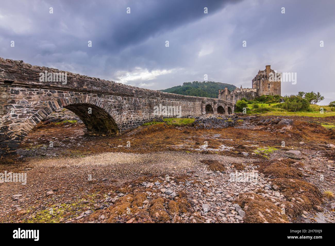 Stone bridge with archways to a historic castle in Scotland. Dry river ...