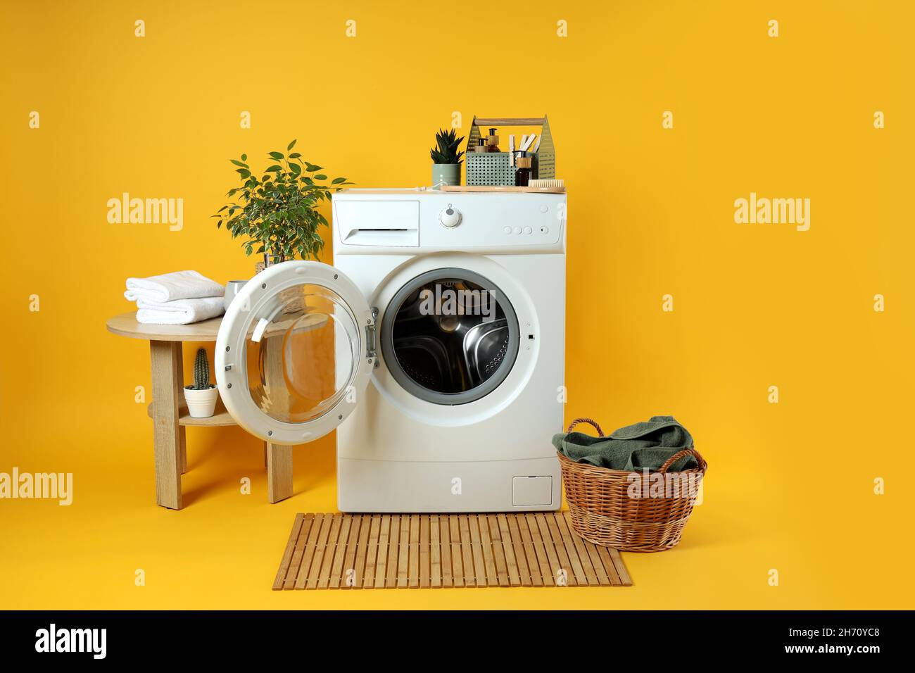 Concept of housework with washing machine on yellow background Stock ...