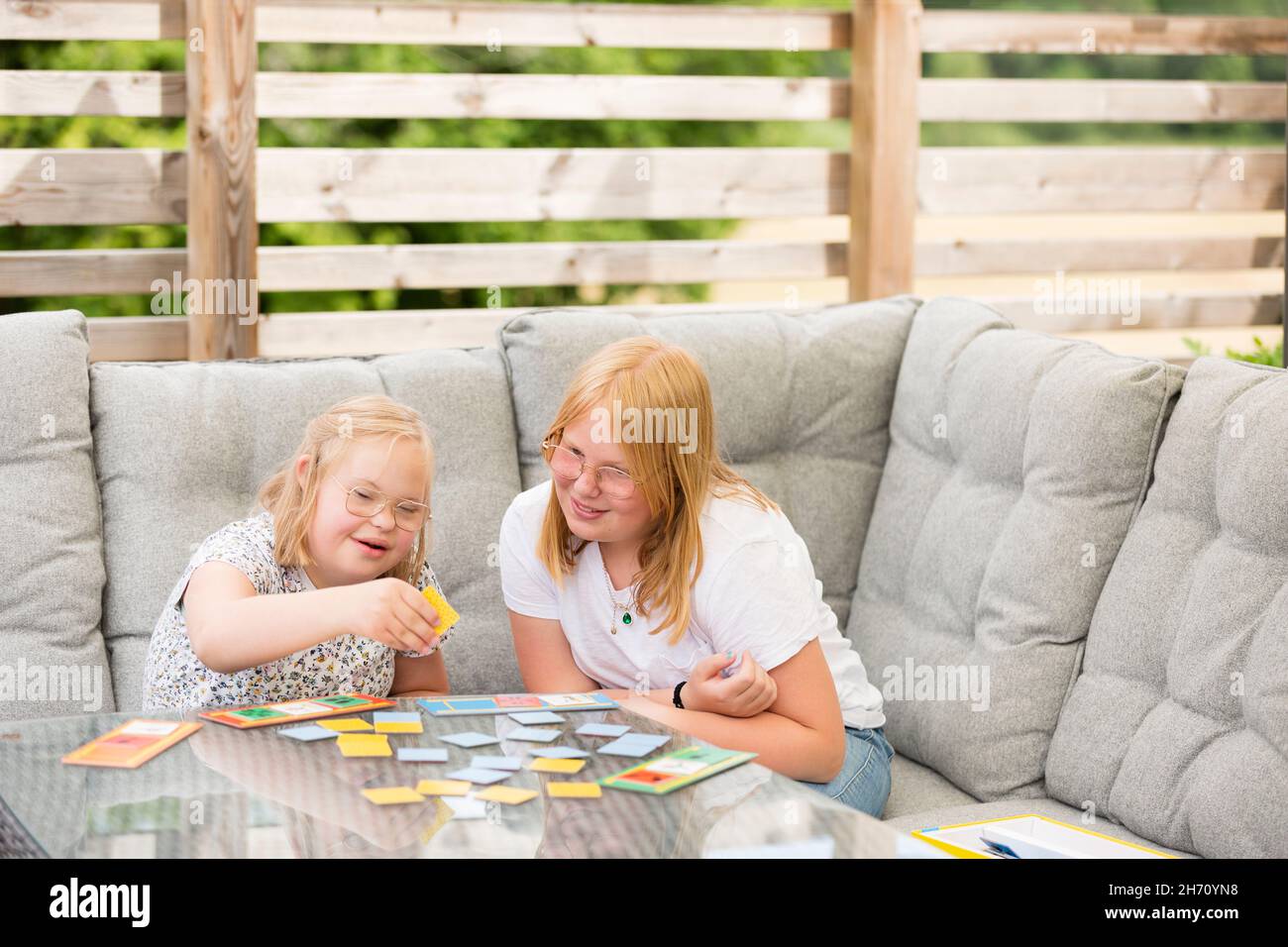 Girls sitting on sofa and playing cards Stock Photo - Alamy