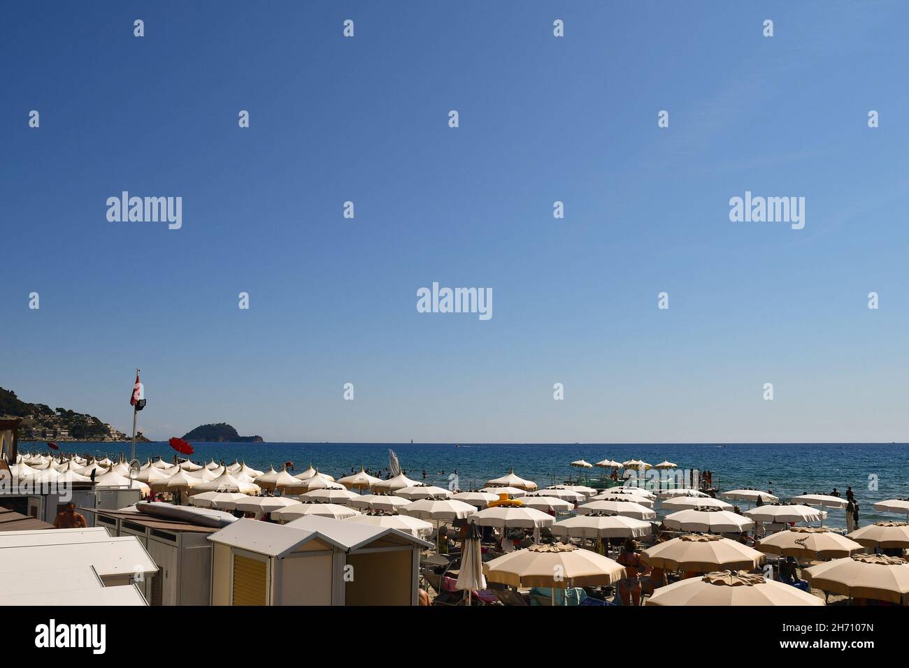 Elevated view of the beach with sun umbrellas and the Gallinara Island over the sea horizon in ...
