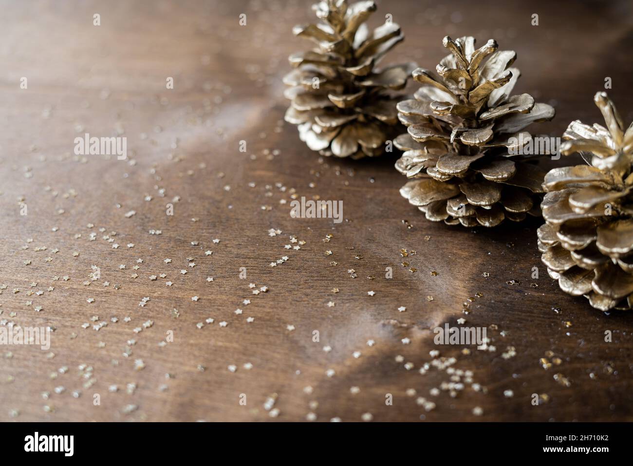 natural golden cones on a wooden table with gold spangles in the shape ...