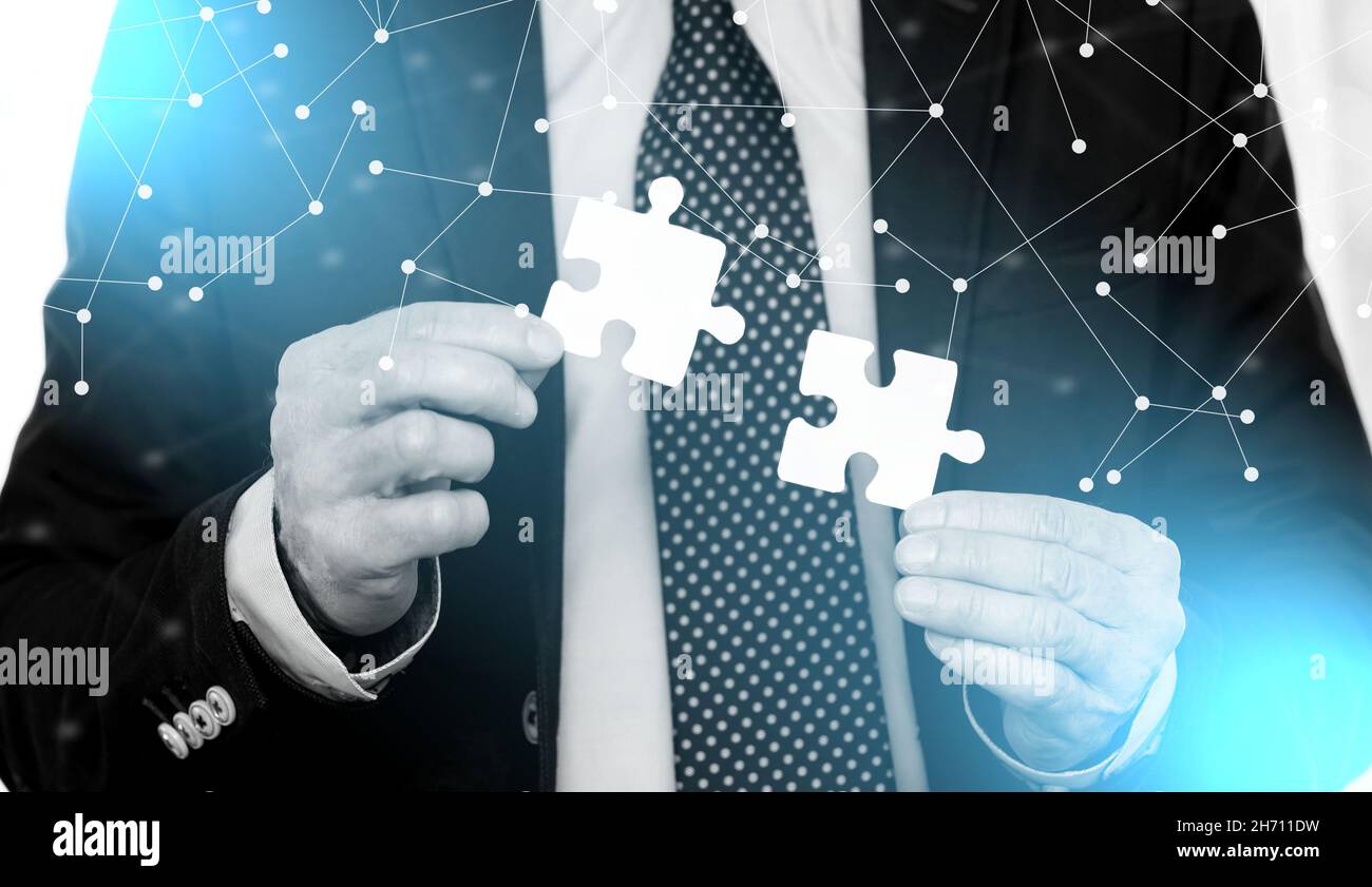 Businessman joining two puzzle pieces, teamwork concept; multiple ...