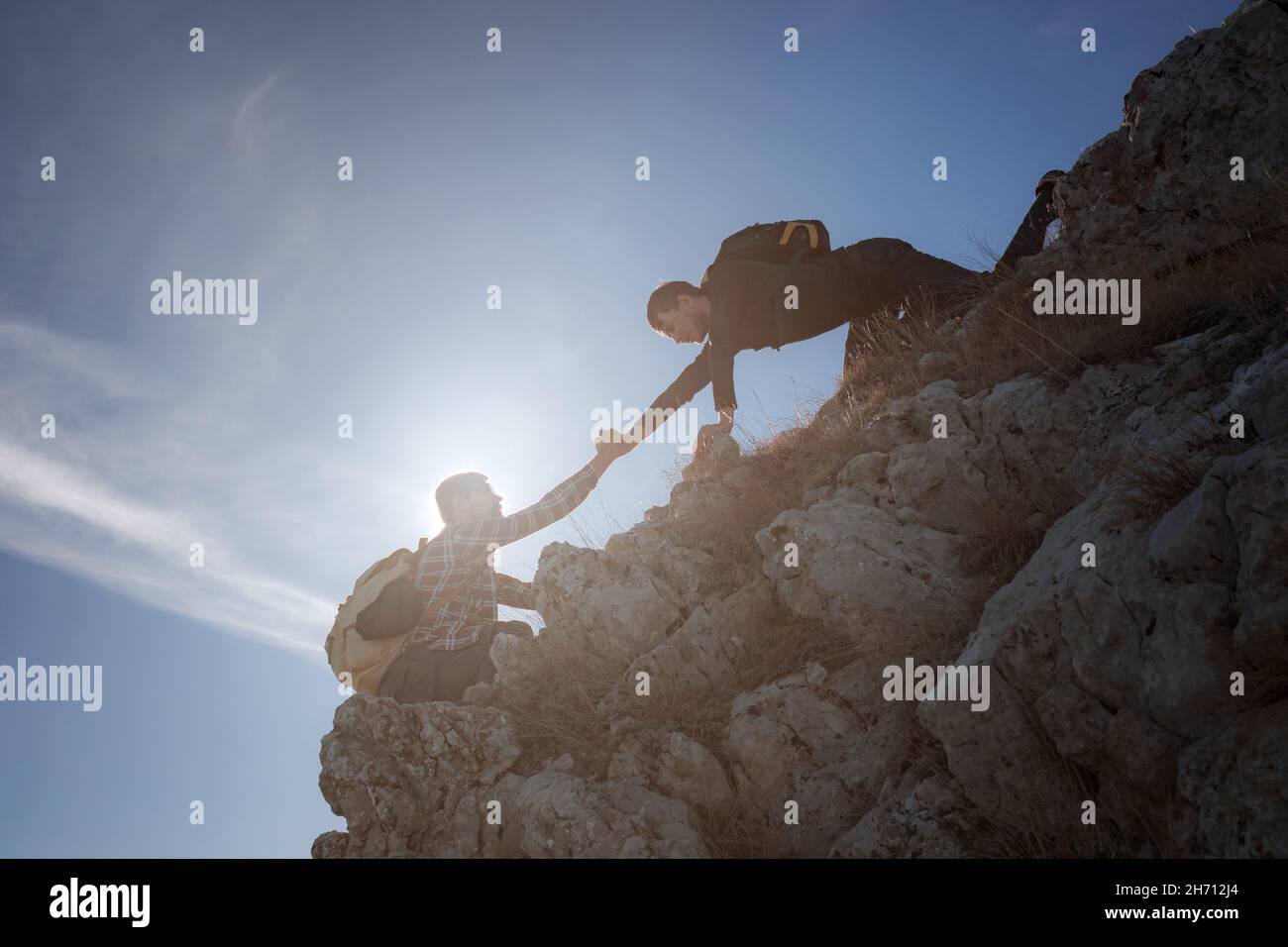 Help and assistance concept. Silhouettes of two people climbing ...