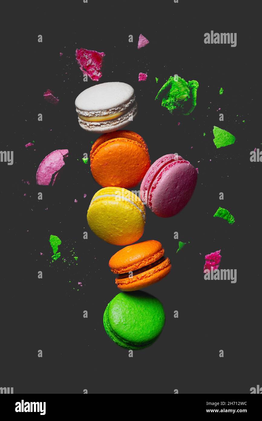 Different types of macaroons in motion falling on black background ...