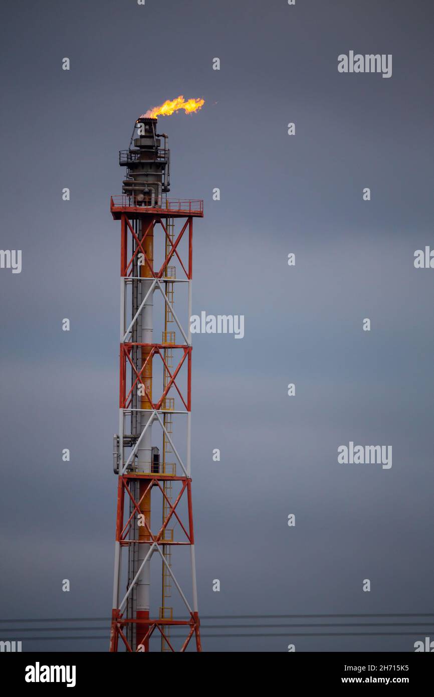 Gas torch at the top of the chimney in the refinery. Photo taken in low ...