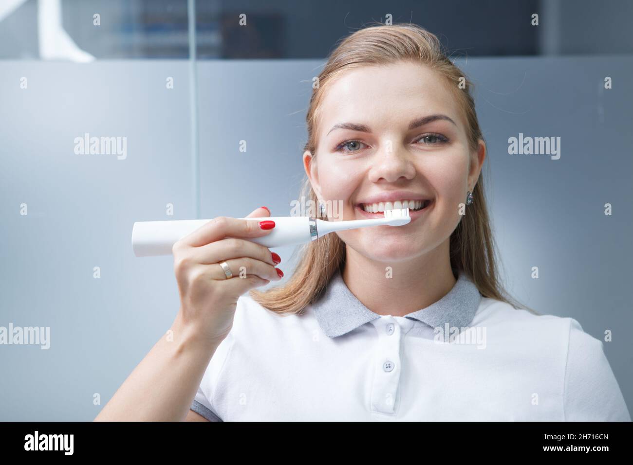 Happy beautiful female dentist smiling, holding up electric toothbrush ...