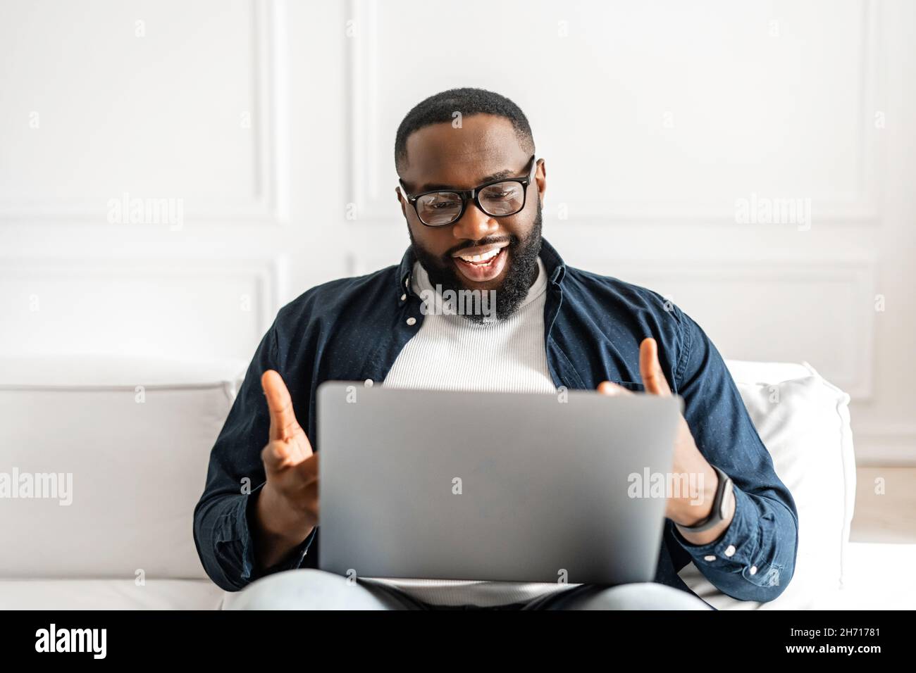Positive African-American guy using laptop for video call sitting on ...