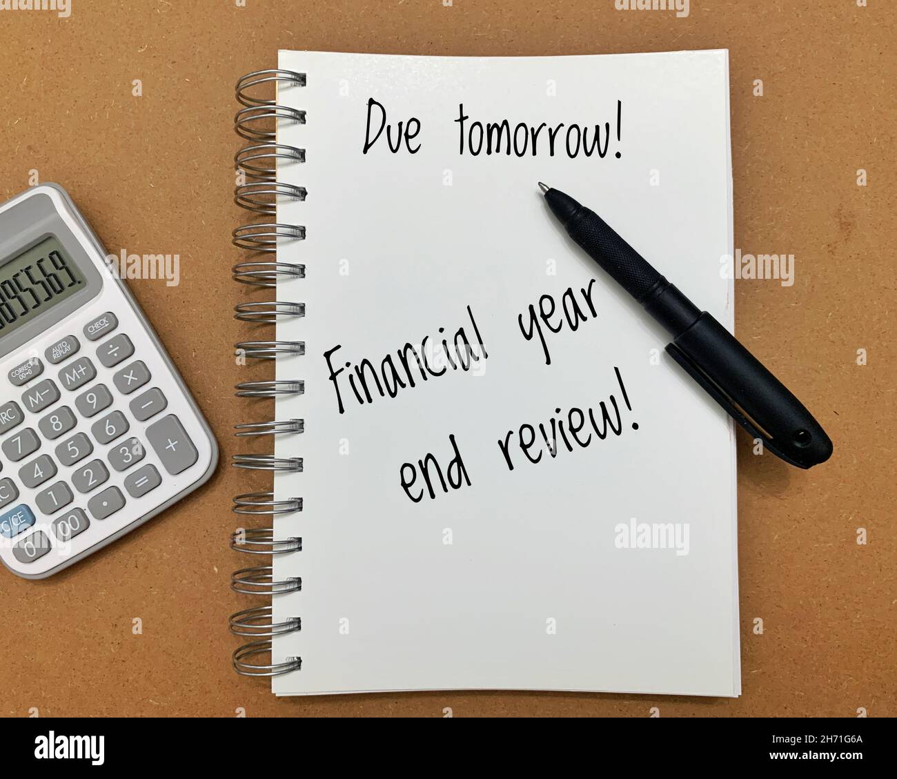 Financial Year end review text on note pad with calculator and pen ...