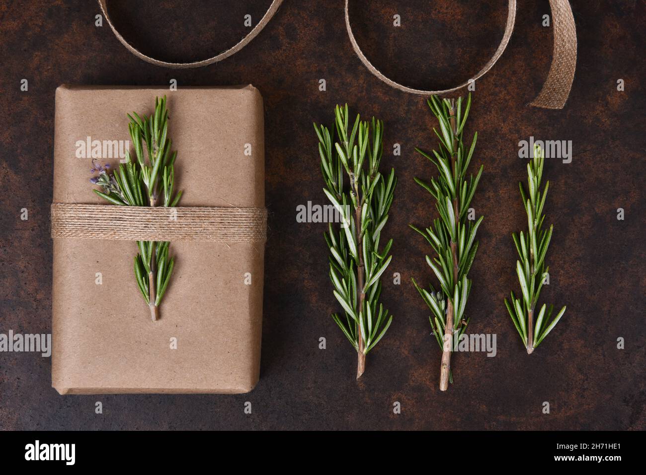 Flat lay still life with a plain brown paper wrapped present, rosemary ...