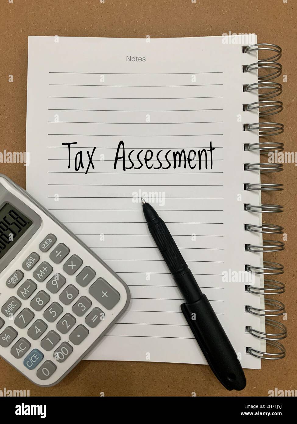 Tax assessment text on note pad with calculator and pen background ...