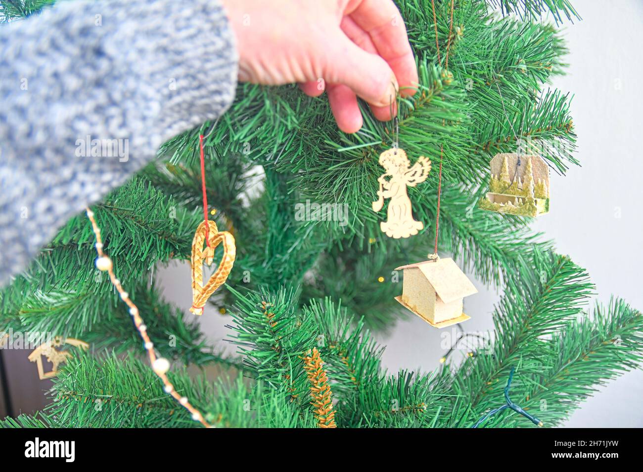Decorating the Christmas tree, holding some decoration in his hand ...
