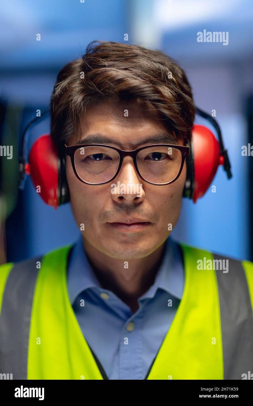 Portrait of asian male engineer wearing ear plugs in computer server ...