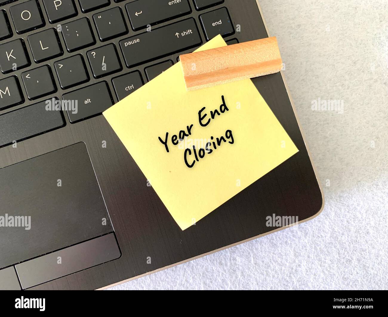 Year end closing text on sticky note with wooden brick and laptop ...