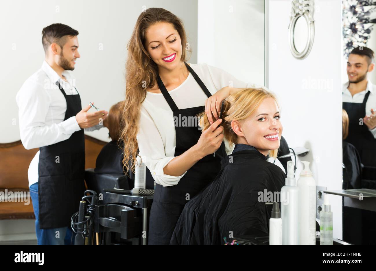 Happy hairdresser doing hairstyle Stock Photo - Alamy