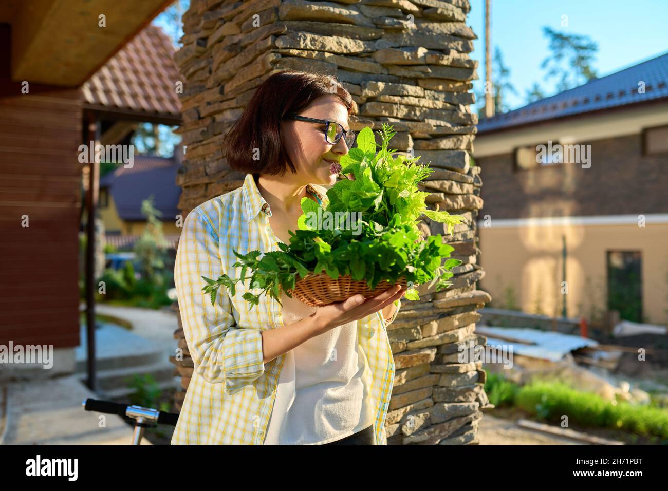 Woman in garden holding basket with freshly picked crop of green spicy ...