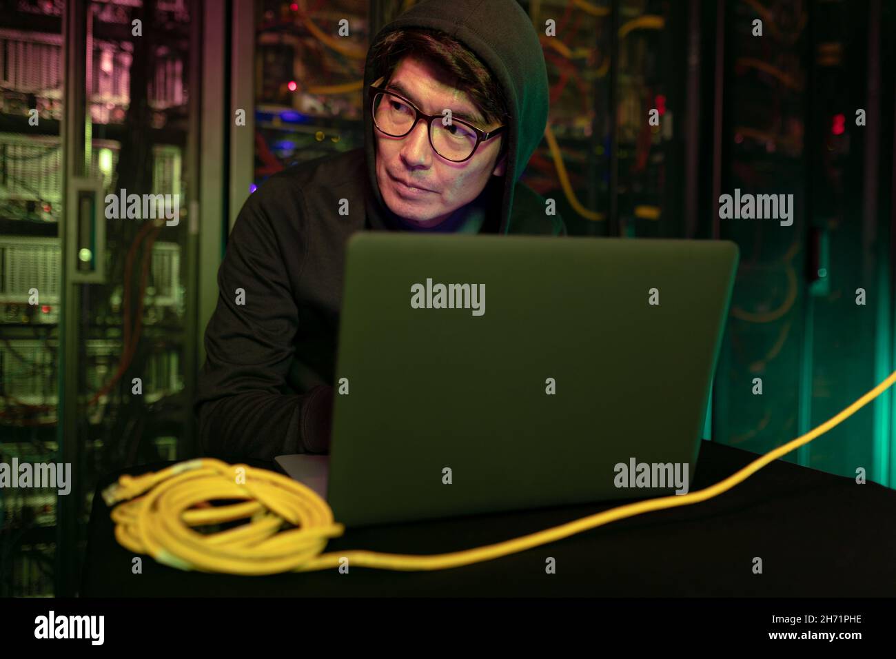 Asian male hacker using a laptop in computer server room Stock Photo ...