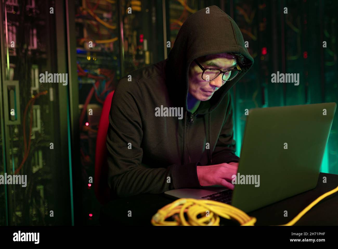 Asian male hacker using a laptop in computer server room Stock Photo ...