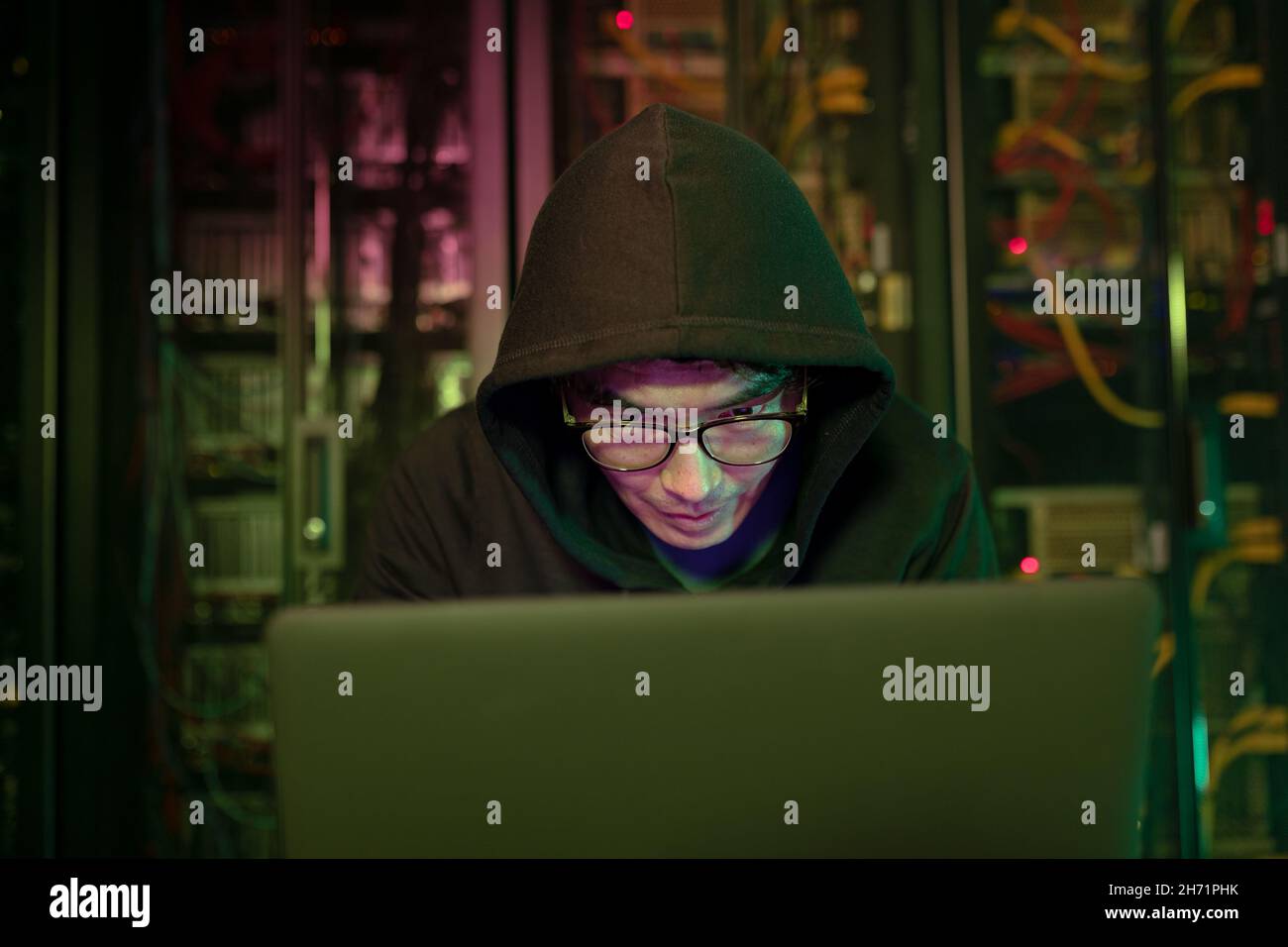 Asian male hacker using a laptop in computer server room Stock Photo ...