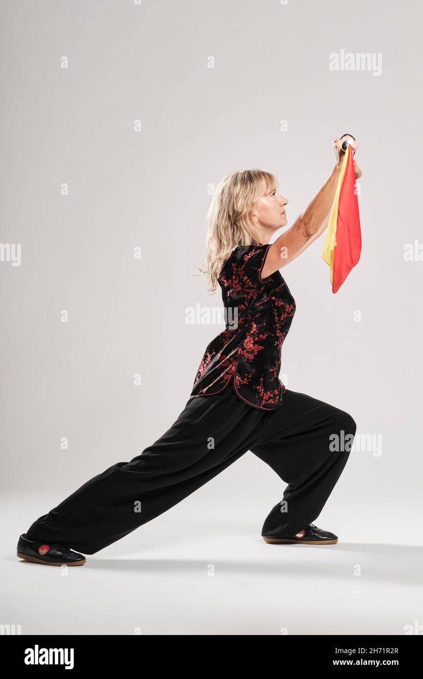 Mature blonde woman practicing Tai Chin with saber in a white ...