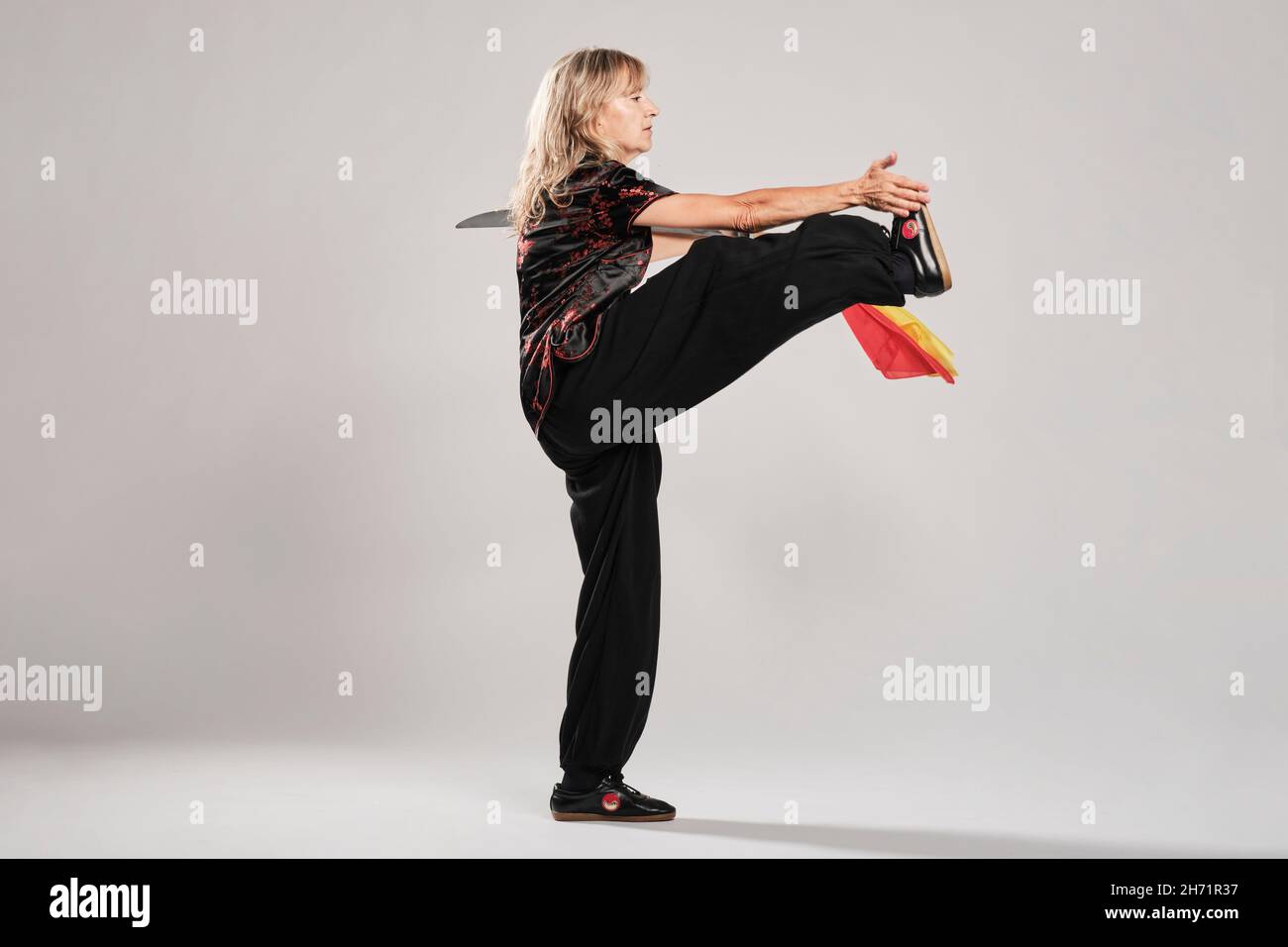 Mature blonde woman practicing Tai Chin with saber in a white ...