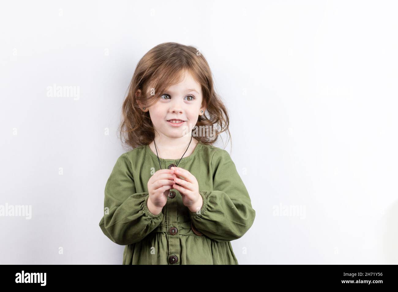 A cheerful little red-haired girl, rolling her eyes, playfully looks up ...