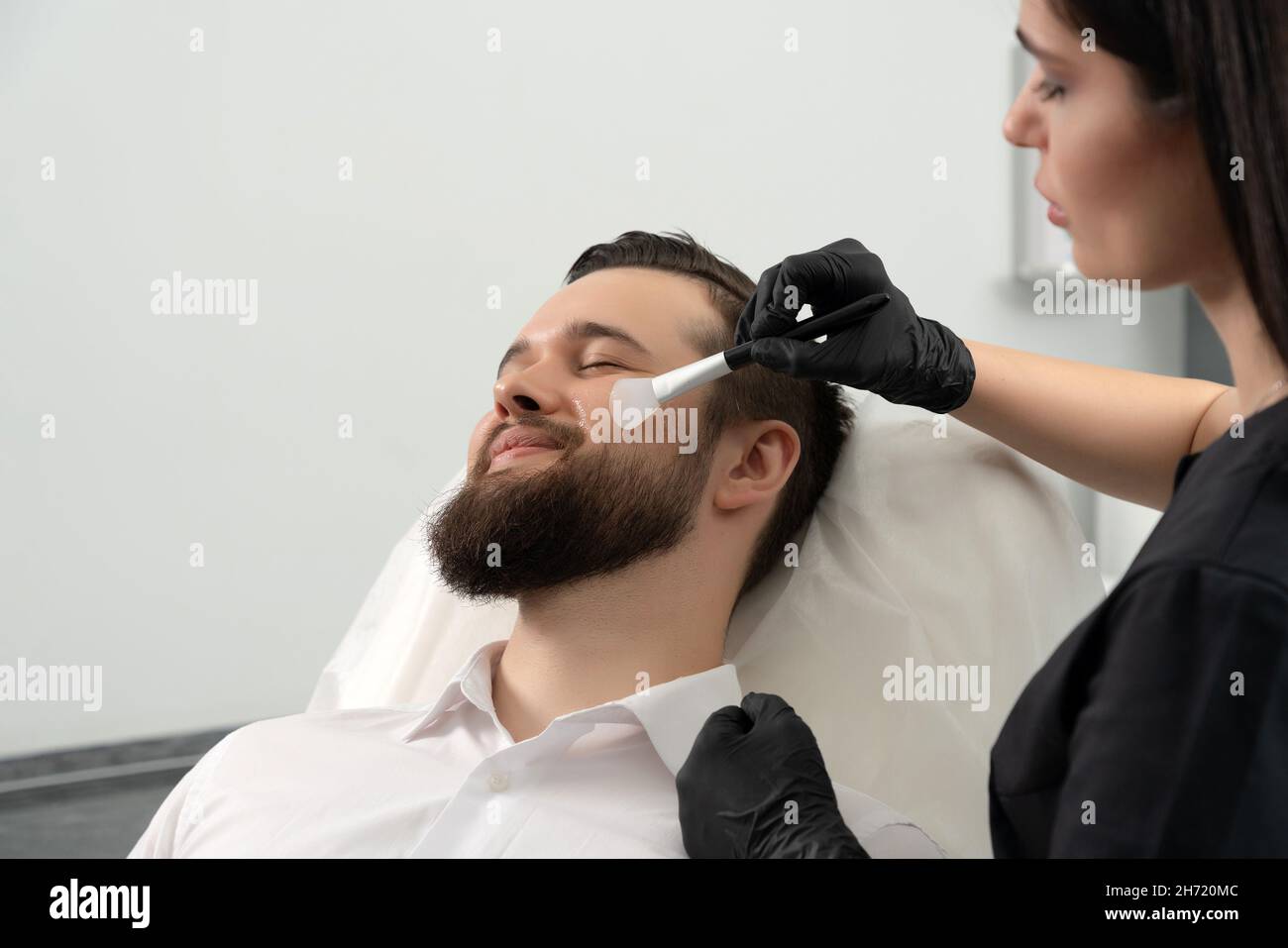 Bearded man getting laser facial treatment by professional ...