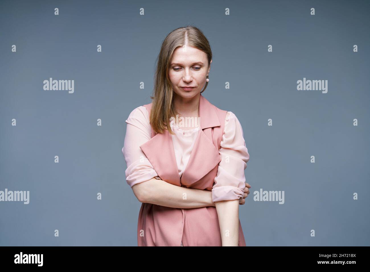 Modest and naive woman with blond hair, stylishly dressed in pink vest ...