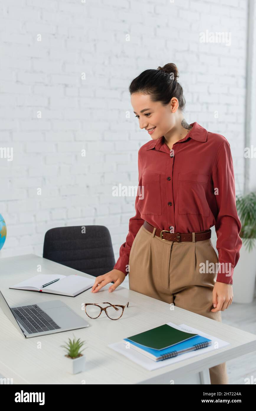 smiling young teacher looking at laptop on desk Stock Photo - Alamy