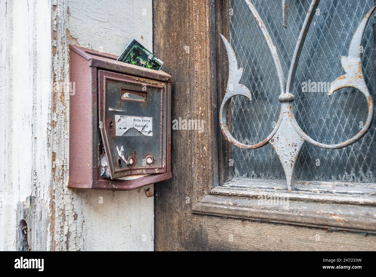 Old rusty dented mailbox at a house entrance with old door and iron ...