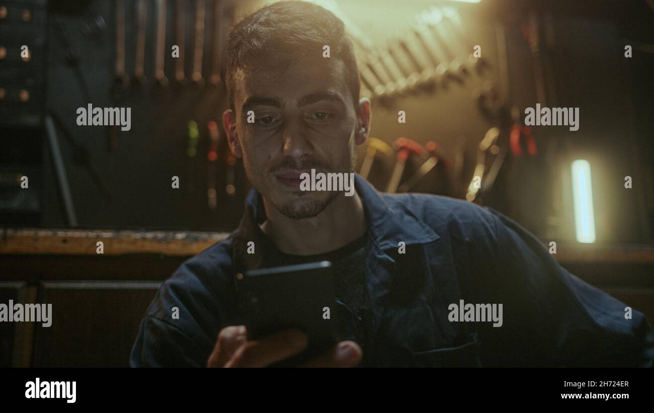 Young handsome blacksmith man sitting in front of the workbench ...