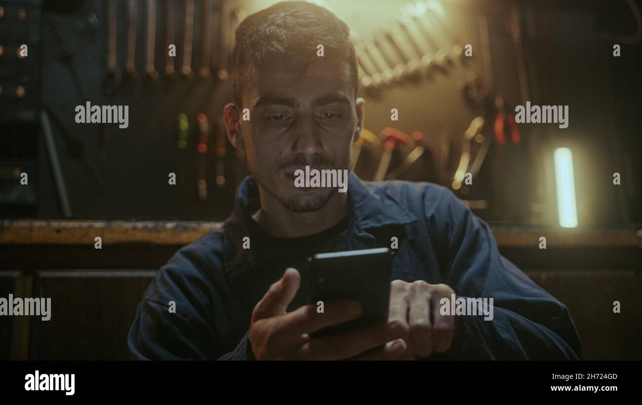 Young handsome blacksmith man sitting in front of the workbench ...