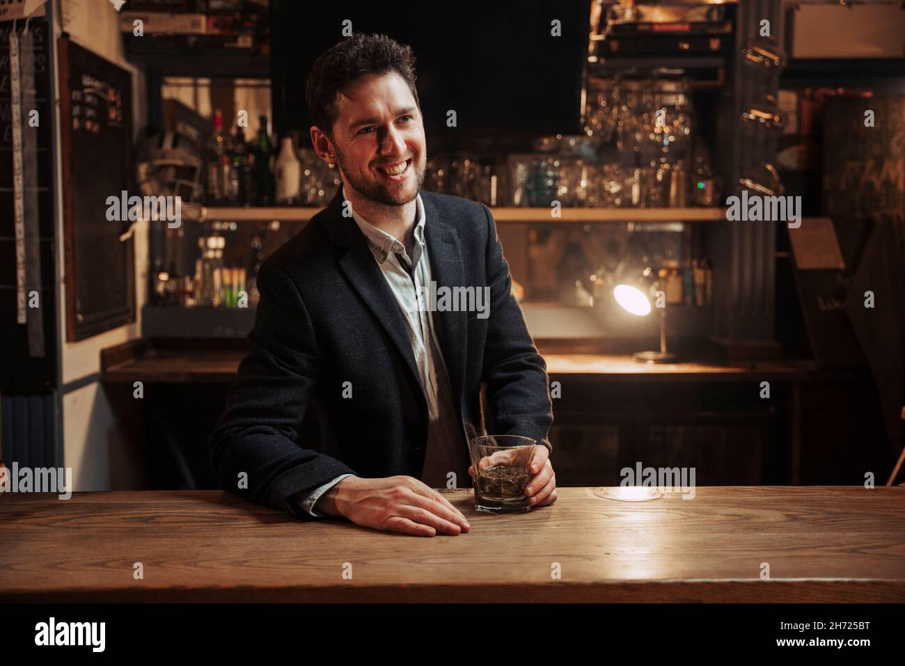 Caucasian male wearing suit smiling drinking whiskey at the bar Stock ...