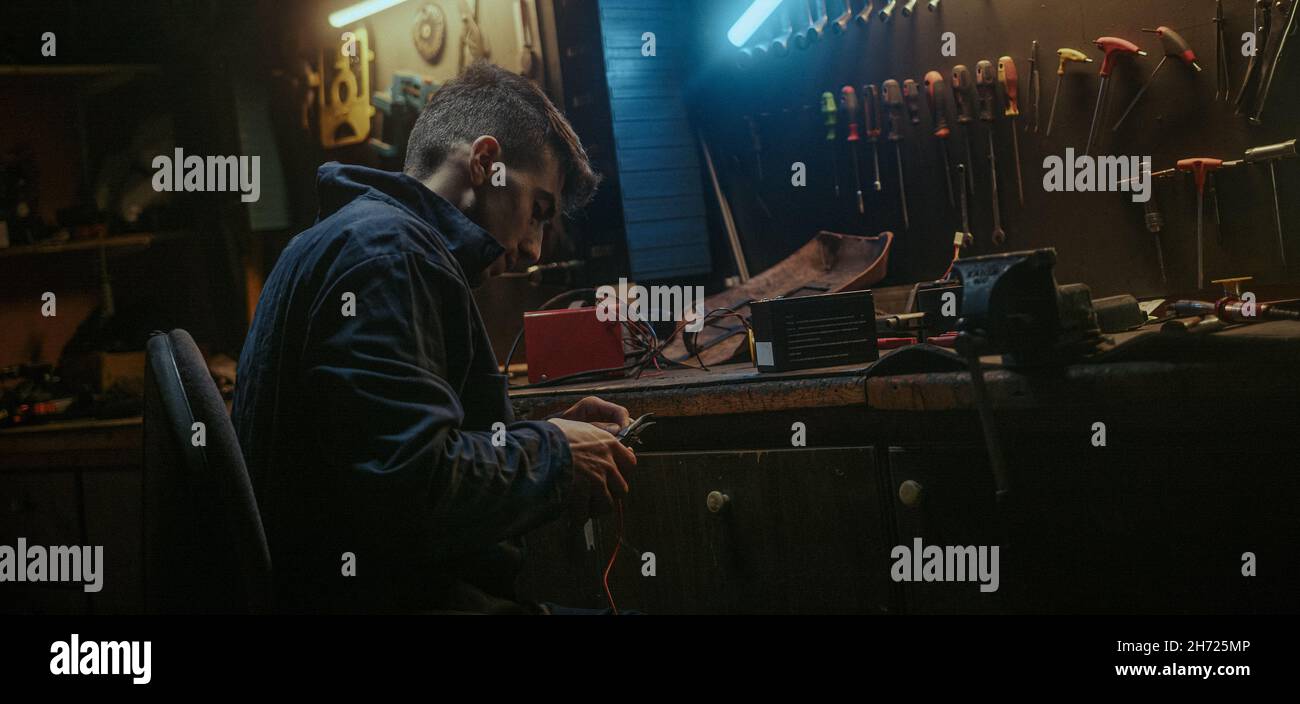 Young blacksmith man with workwear standing up and get proper tool for ...