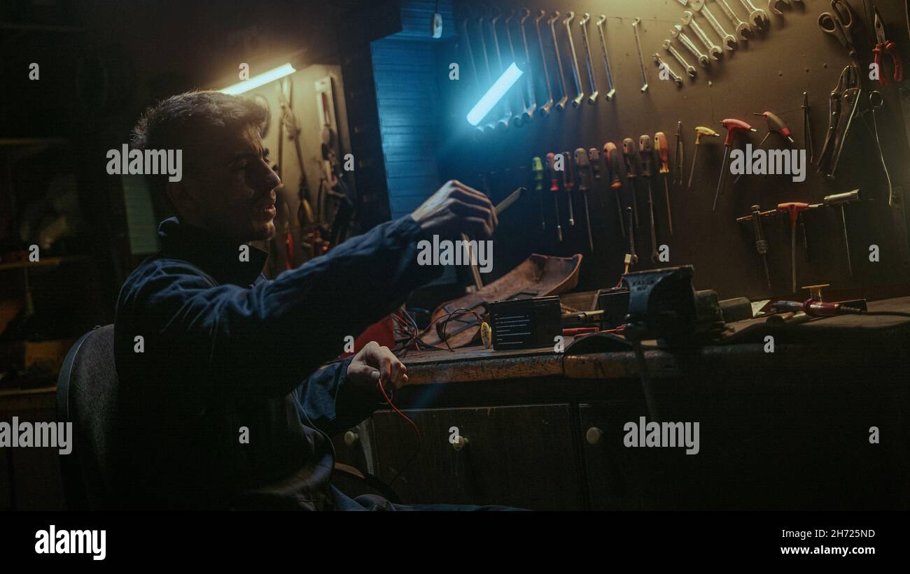 Young blacksmith male with workwear sitting on chair, taking ...