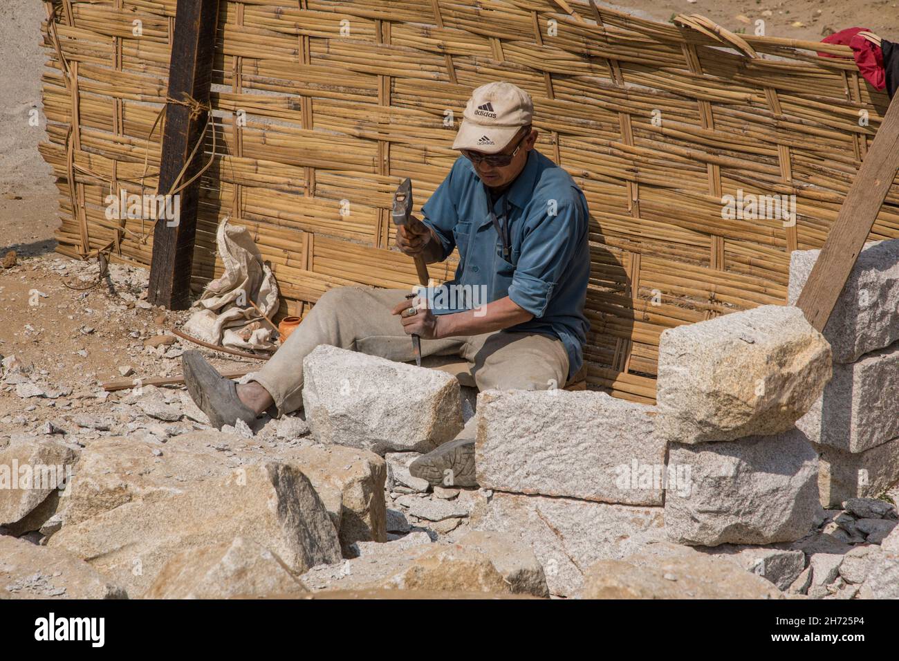 A Bhutanese stone mason shapes stones by hand for building in Thimphu ...