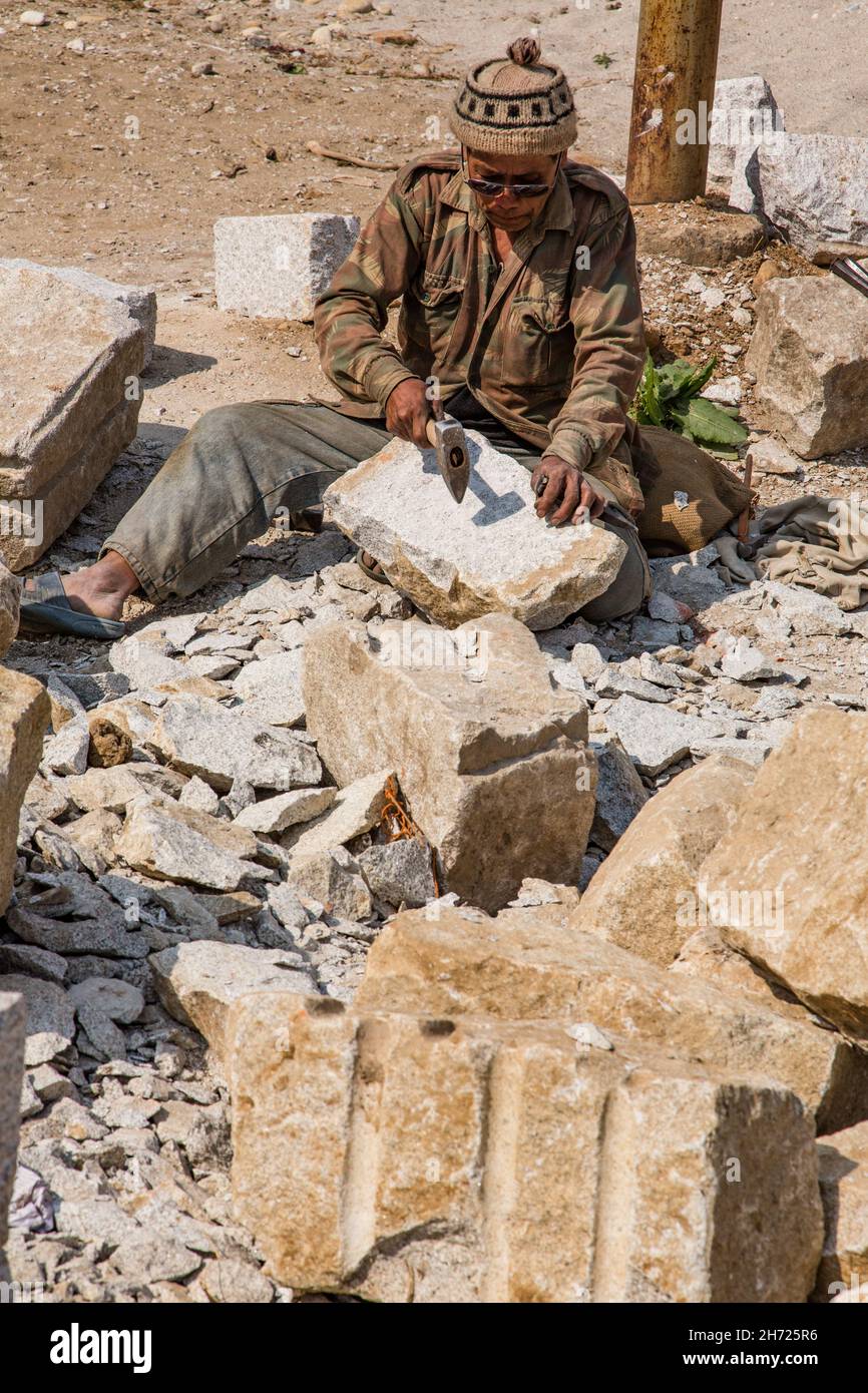 A Bhutanese stone mason shapes stones by hand for building in Thimphu ...