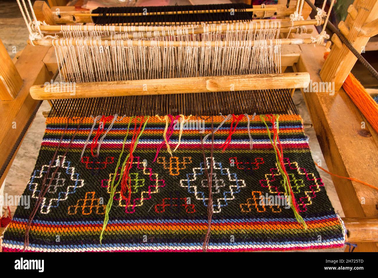 A partially-completed rug on a hand loom with geometric designs in ...