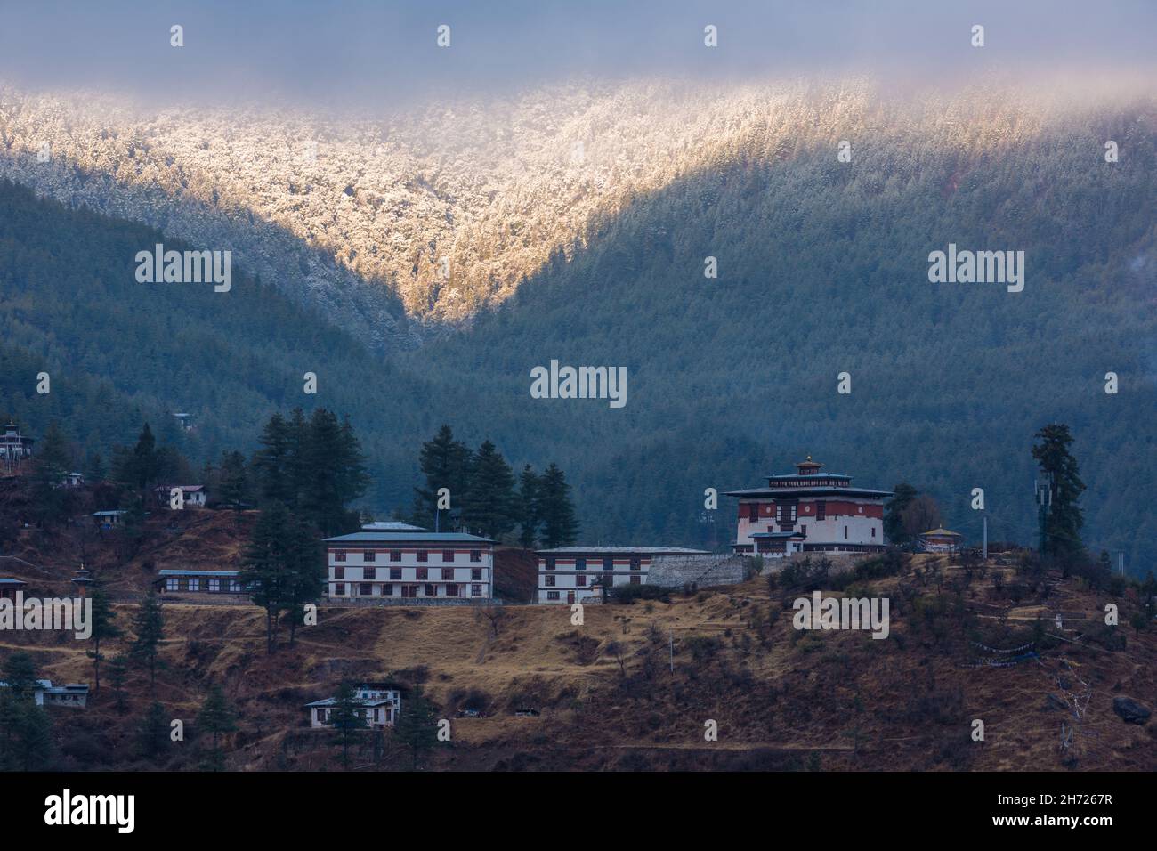 Sunrise on the snow-dusted forest above the Dechen Phodrang Monastery ...