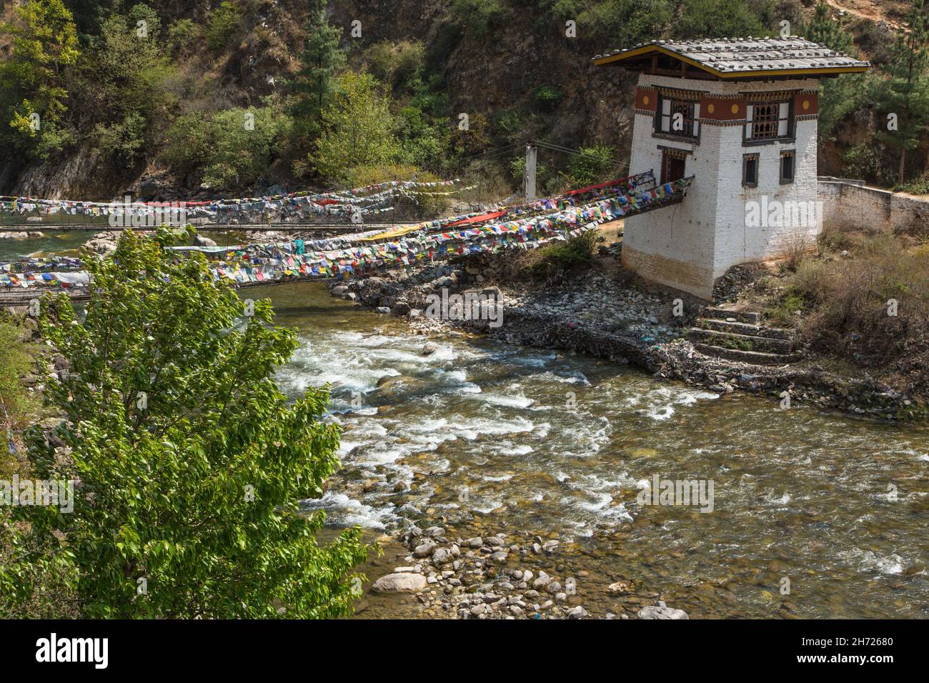 Prayer flags line the last remaining iron chain bridge in Bhutan over ...