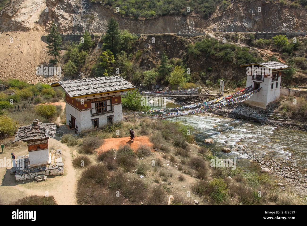Prayer flags line the last remaining iron chain bridge in Bhutan over ...