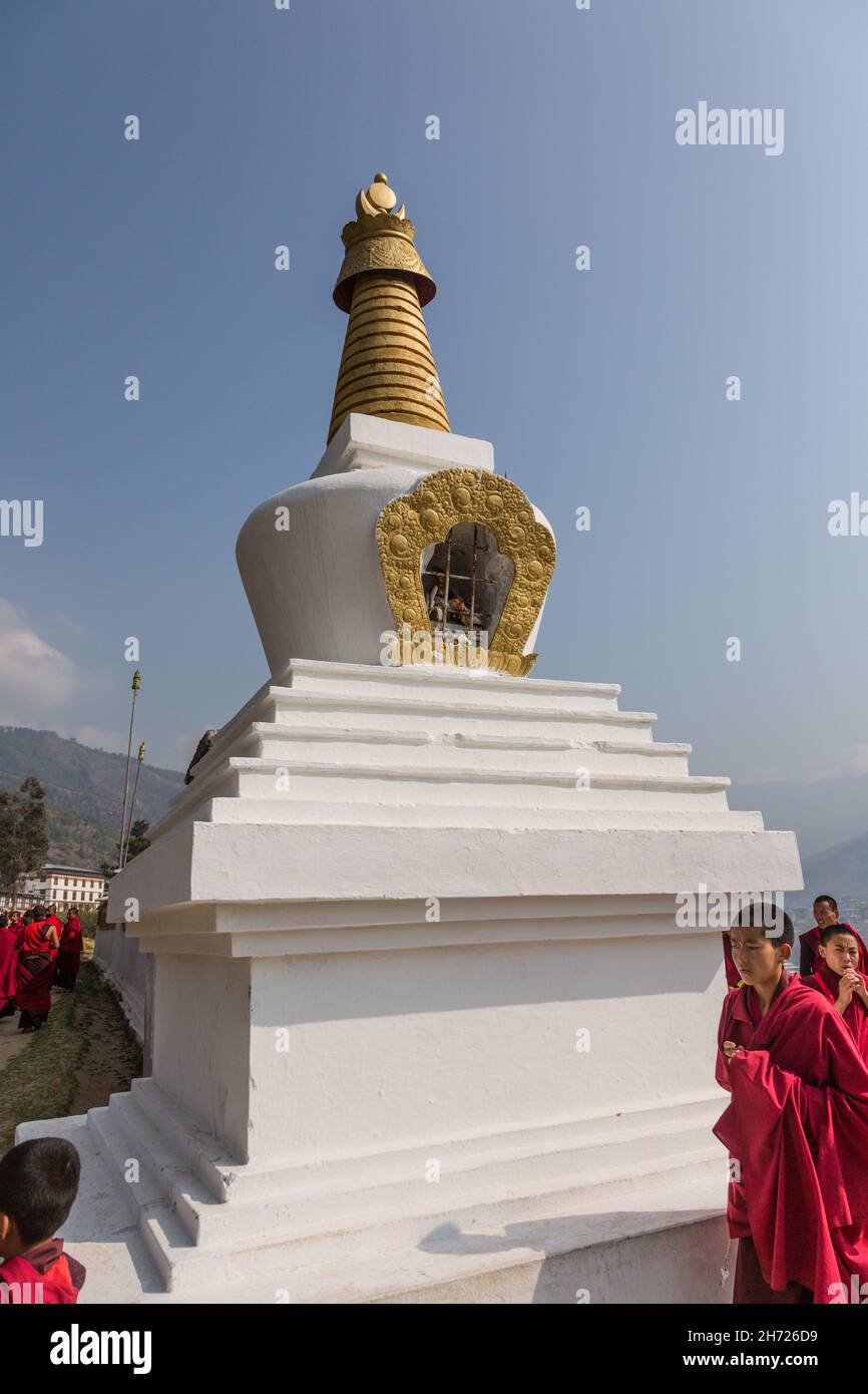 Young monastic novices walk by a Tibetan-style stupa at the Dechen ...