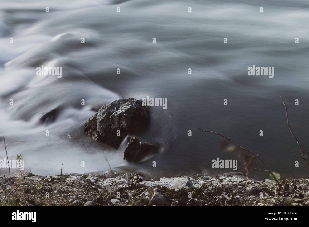 Long exposure photography of single, submerged stone lying in the river ...