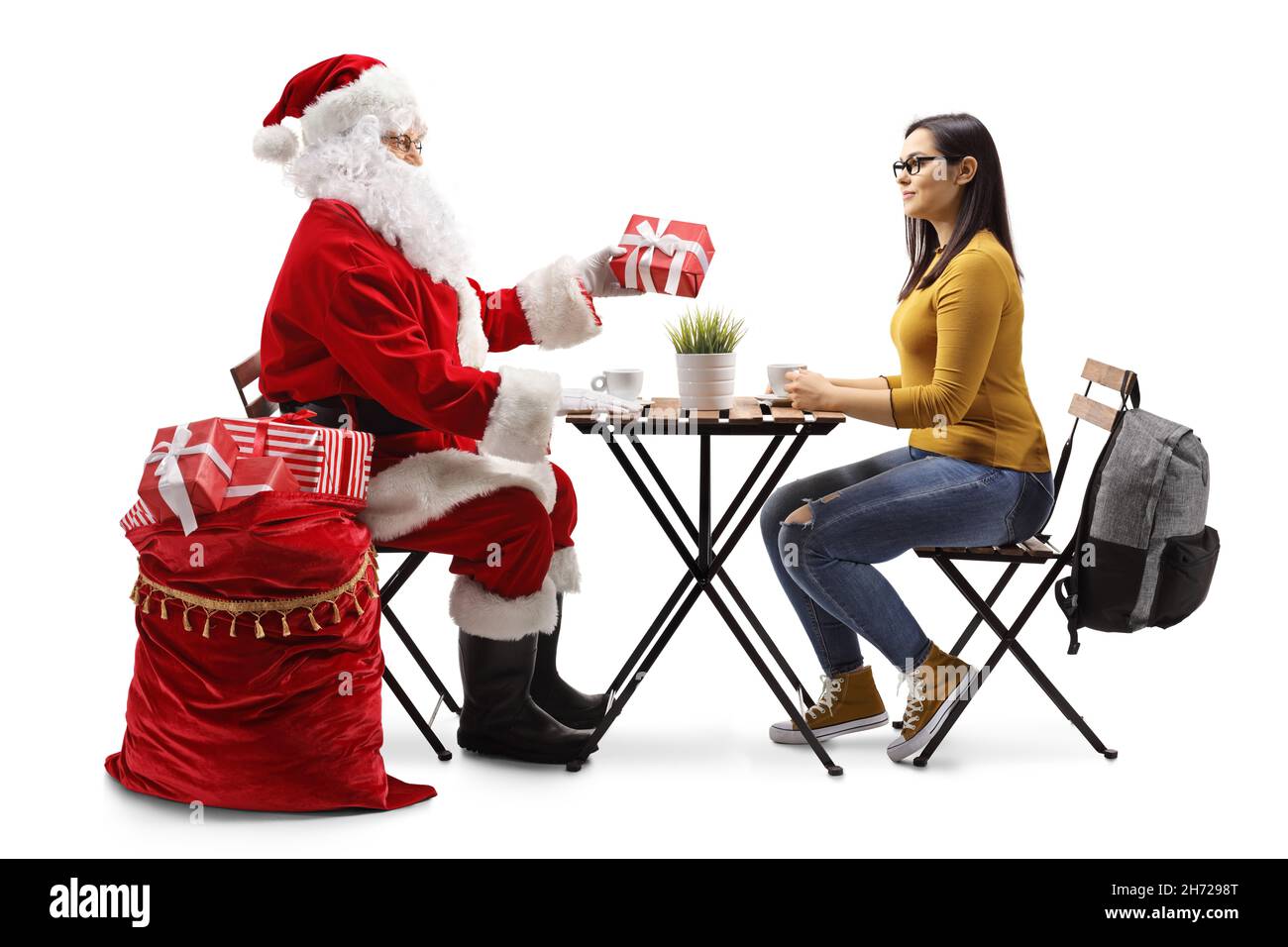 Santa Claus sitting at a table and giving a christmas present to a ...