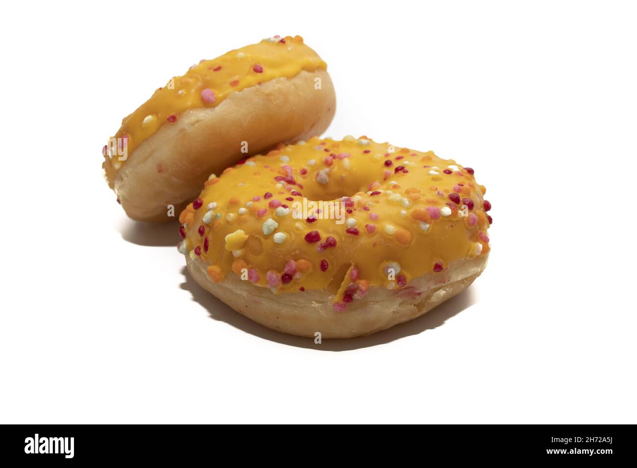 Freshly baked orange donuts decorated with colorful sprinkles isolated ...