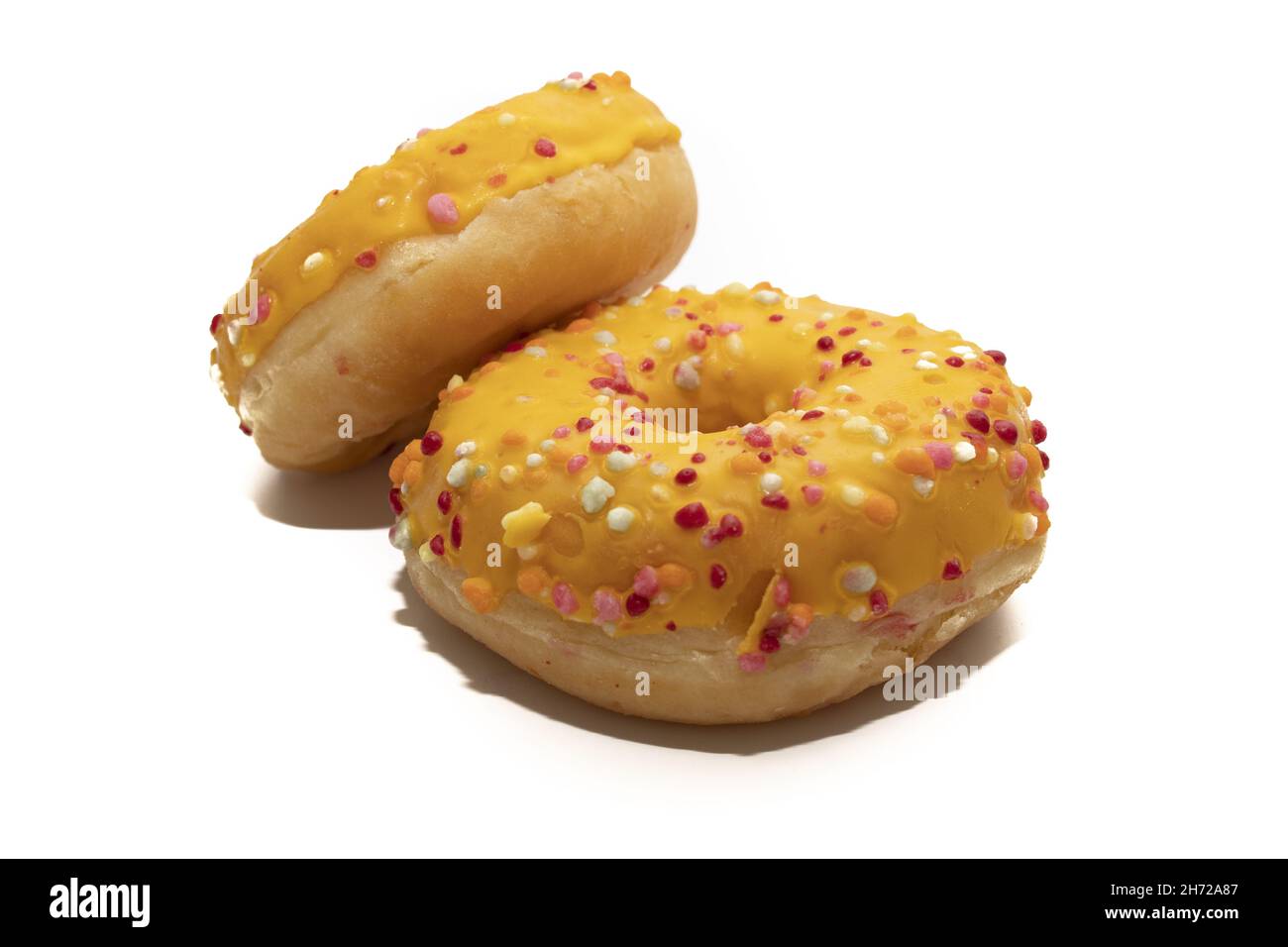 Freshly baked orange donuts decorated with colorful sprinkles isolated ...