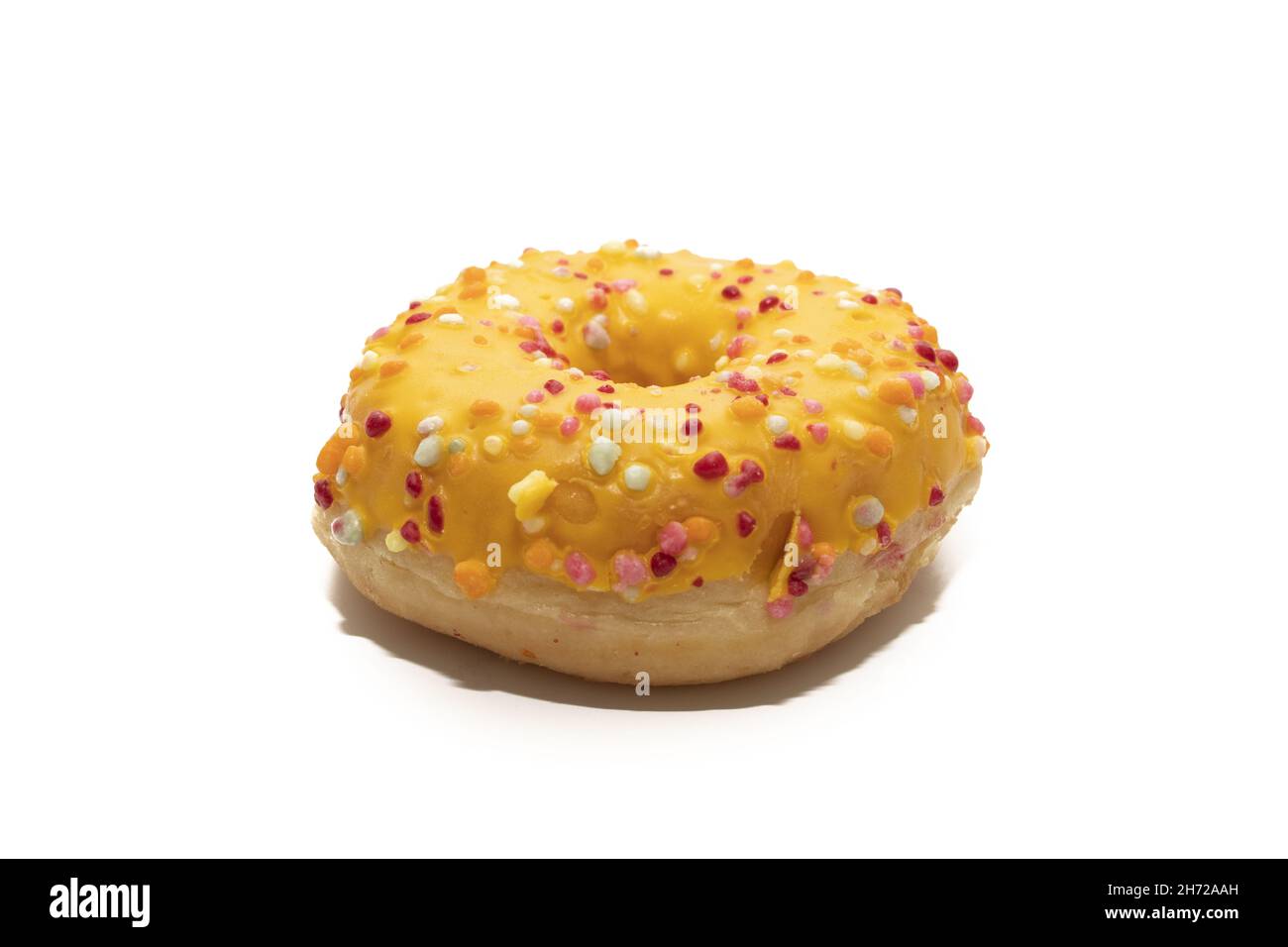 Freshly baked orange donut decorated with colorful sprinkles isolated ...