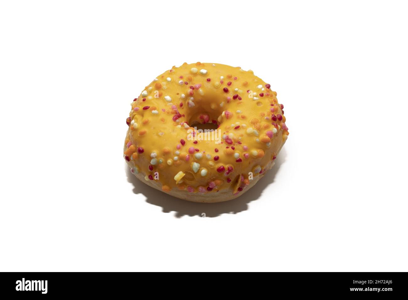 Freshly baked orange donut decorated with colorful sprinkles isolated ...