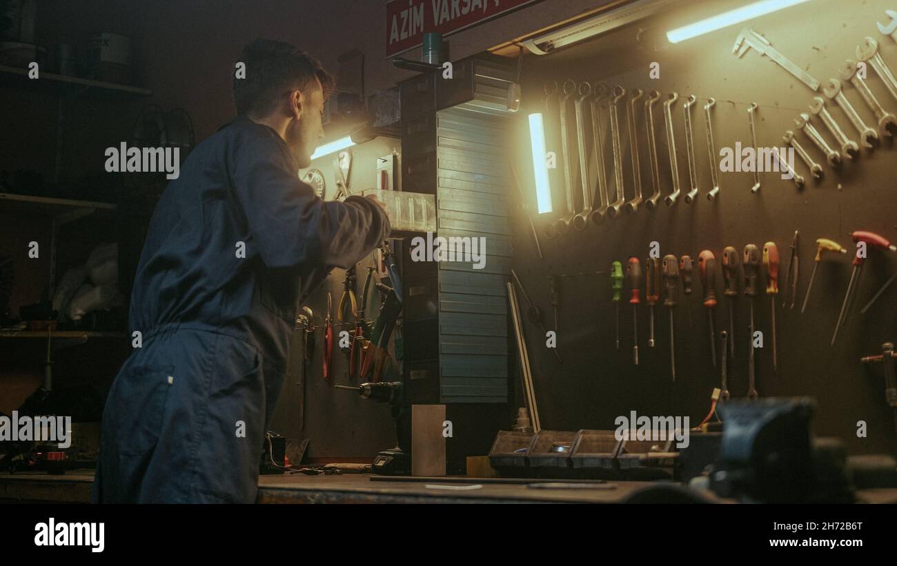 Male young blacksmith man putting his tools and equipment in place in ...