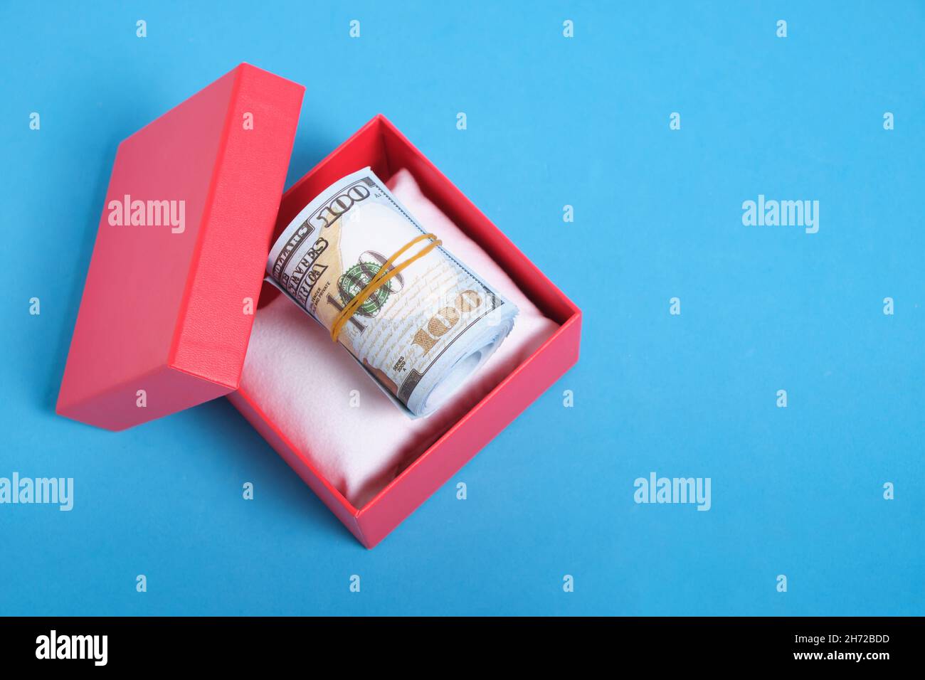 Roll of hundred dollar bills in red gift box on blue background Stock ...