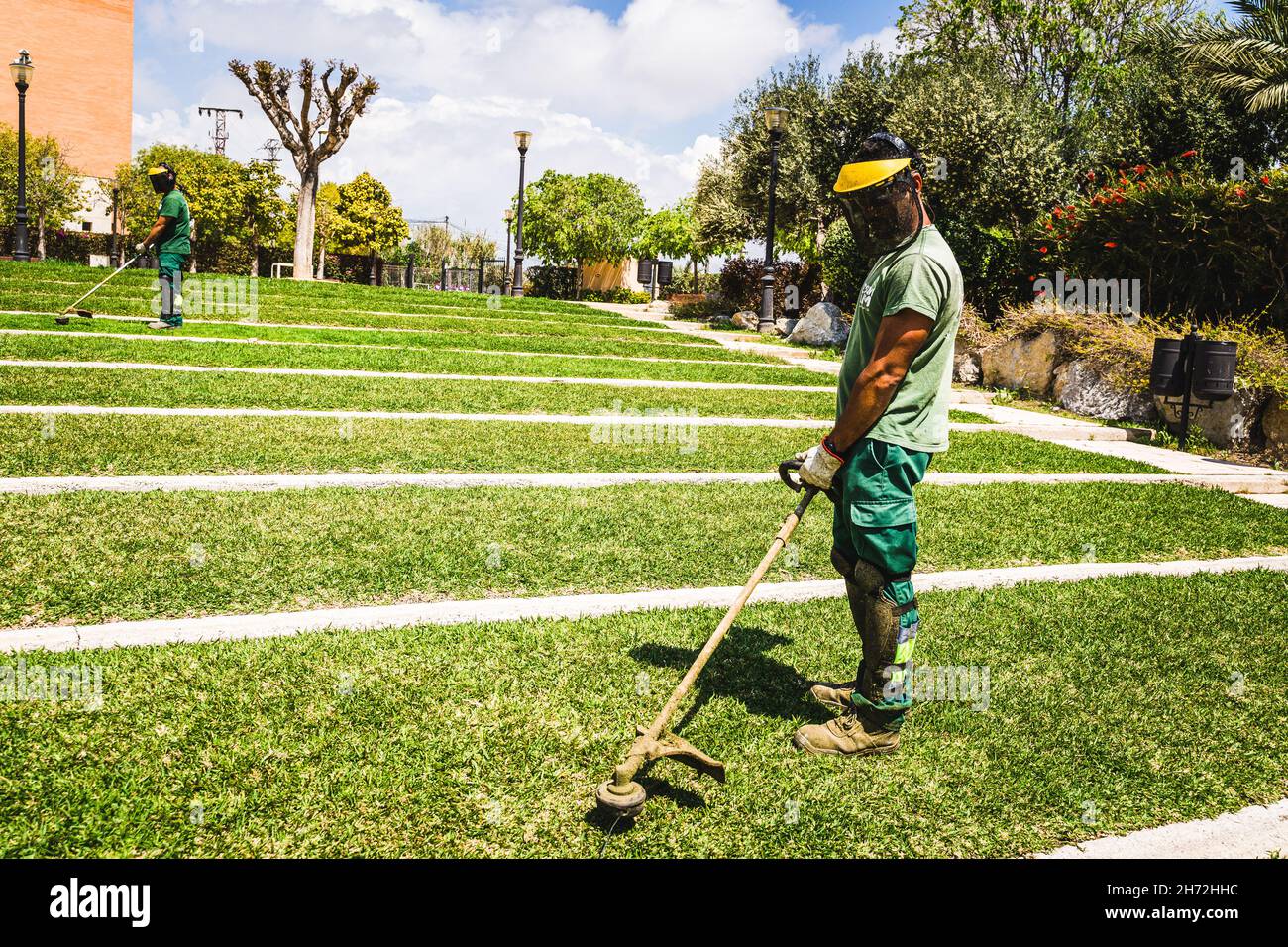 Worker in a special uniform doing lawn mowing in the yard Stock Photo ...